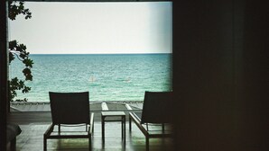 Quarto com duas cadeiras de frente para uma grande janela com vista para o mar.