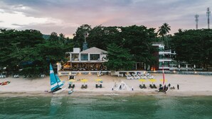 Uma propriedade à beira-mar com área de jantar, cadeiras de descanso e uma tenda na areia.