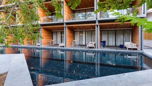 Um edifício moderno de vários andares com fachada de vidro, terraço no telhado e piscina.