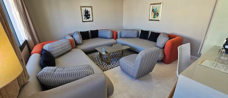 Uma sala de estar moderna com um sofá modular, poltronas, uma mesa de centro e duas obras de arte emolduradas nas paredes.