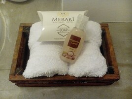 Uma bandeja de madeira com uma toalha branca e um frasco de shampoo Macadamia Care.