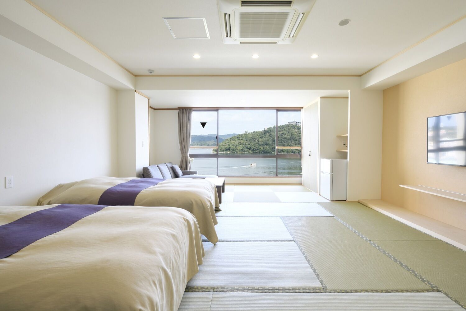 Quarto de hotel com duas camas, vista para a água e varanda.