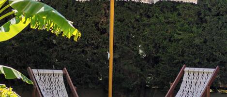 Uma cadeira-rede sob um guarda-sol grande em um jardim bem cuidado.