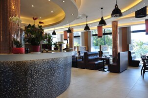 Um lobby de hotel moderno com balcão de recepção curvo, área de estar e grandes janelas.