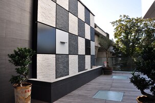 Um edifício moderno com fachada xadrez, deck de madeira e plantas em vasos.