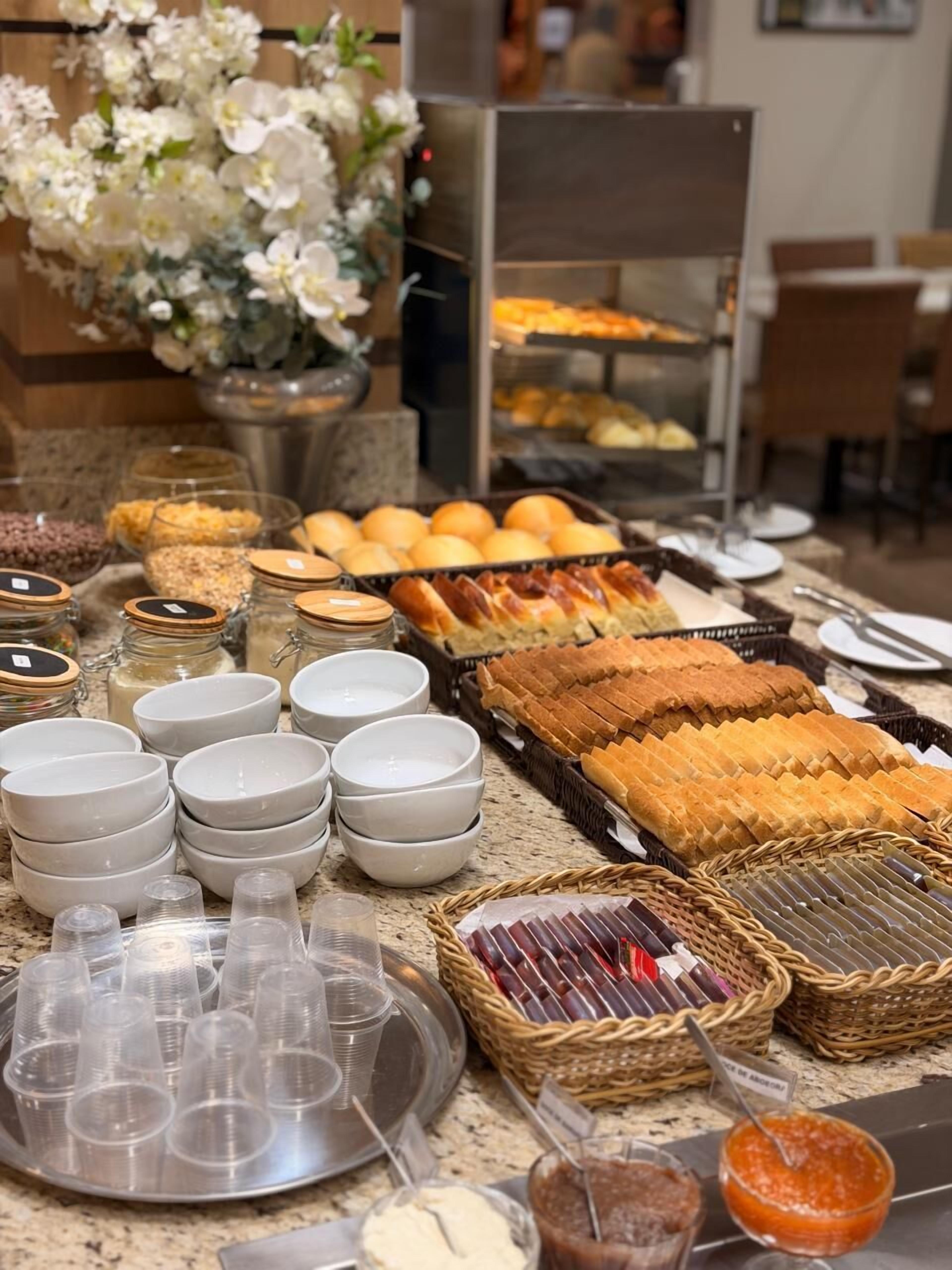 Buffet com diversos alimentos, incluindo pão, acompanhamentos e tigelas.