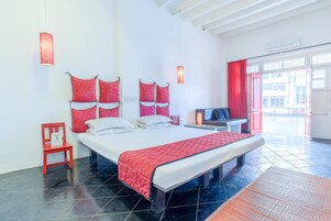 Quarto de hotel com uma cama grande, uma pequena mesa e uma cadeira.