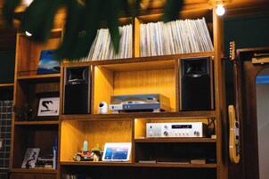 Um quarto com prateleiras de madeira contendo livros, um toca-discos e alto-falantes.