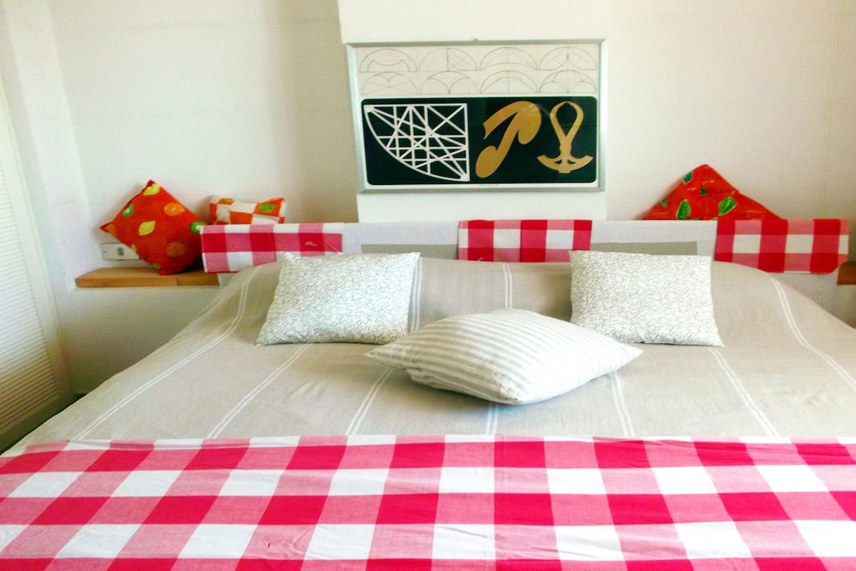 Cama com colcha xadrez, travesseiros e uma obra de arte pendurada acima.
