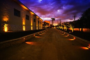 Um caminho pavimentado que leva a um edifício com paredes de pedra e janelas iluminadas.