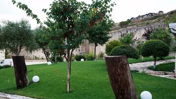 Um jardim bem cuidado com gramado, árvores e esferas brancas.