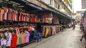 Mercado de rua com diversos quiosques de roupas.