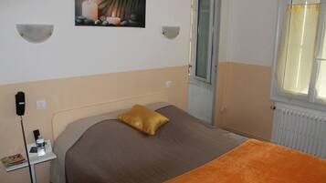 Quarto com cama, mesa de cabeceira com abajur, telefone e um quadro na parede.