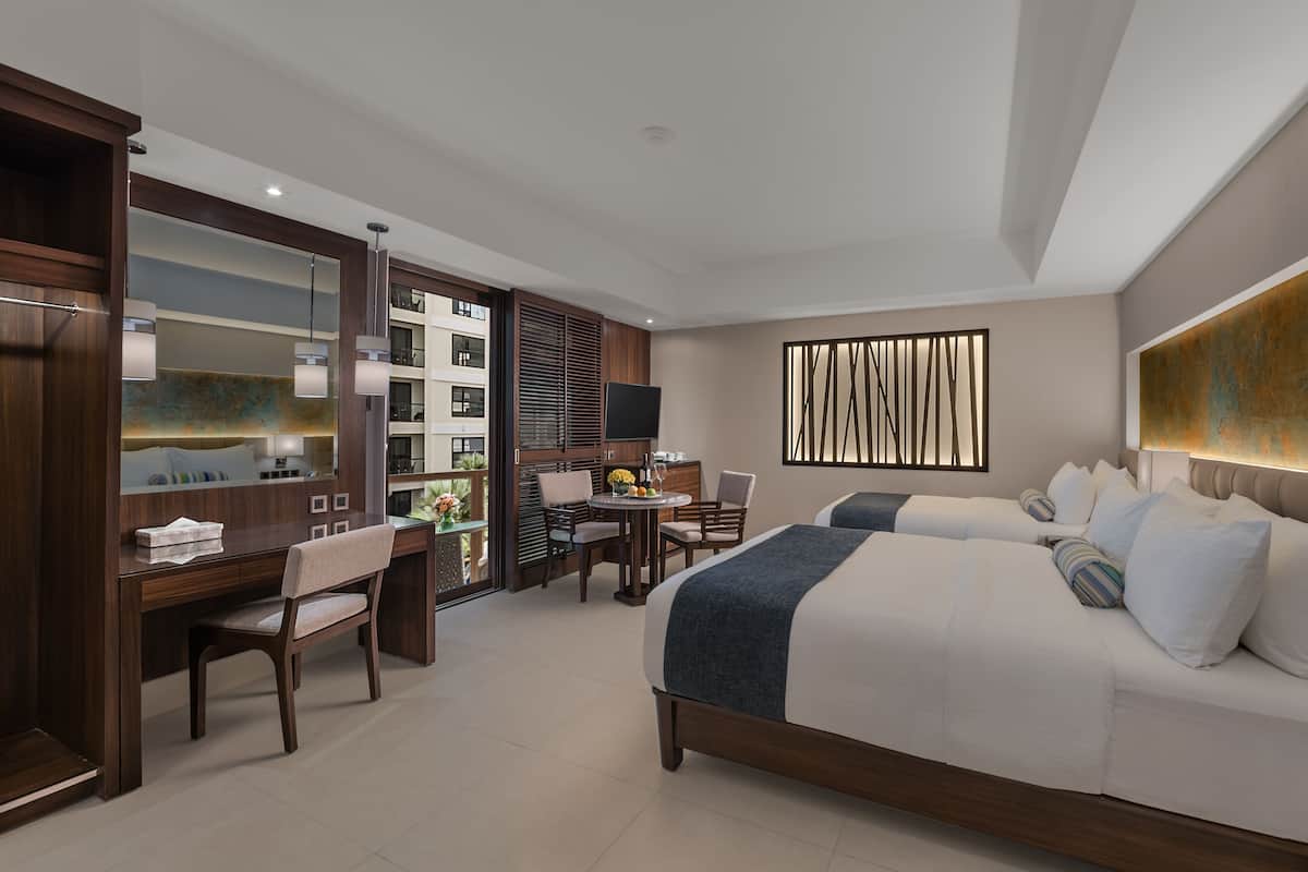 Quarto de hotel com cama, escrivaninha, cadeira e televisão.