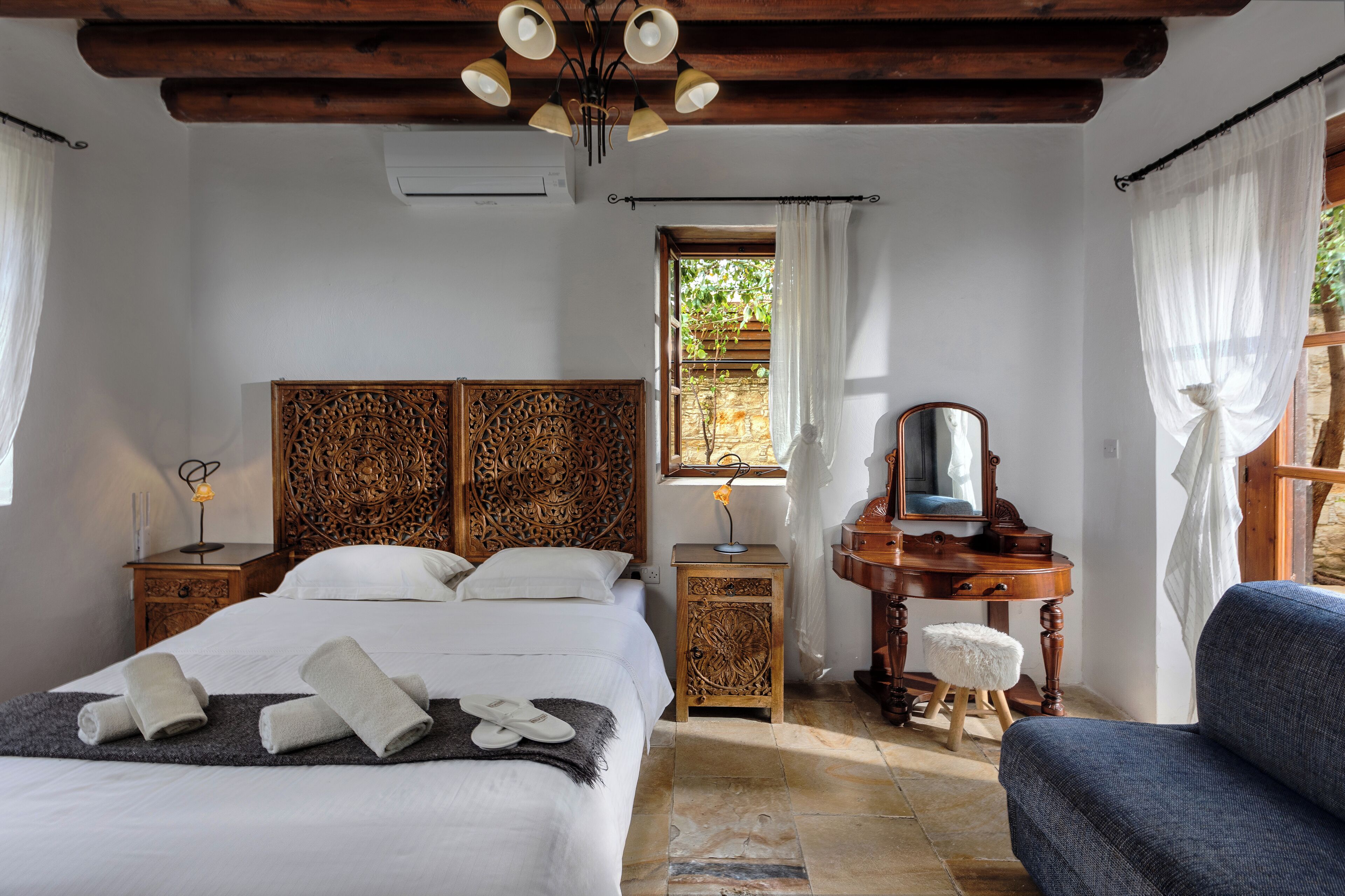 Quarto com uma cama grande, cabeceira de madeira, mesas de cabeceira, cômoda e espelho.