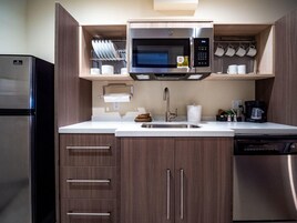 Uma cozinha compacta com geladeira de aço inoxidável, micro-ondas e máquina de café.