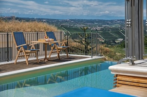 Uma área à beira da piscina com mesa e cadeiras, com vista para uma paisagem deslumbrante.