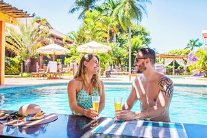 Uma área à beira da piscina com espreguiçadeiras, guarda-sóis e piscina.