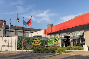 Um edifício com toldo vermelho, mesas ao ar livre e bandeiras.
