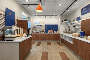 Uma área de café da manhã moderna, com uma seção de padaria, um canto para café e uma placa indicando o local do café da manhã expresso.