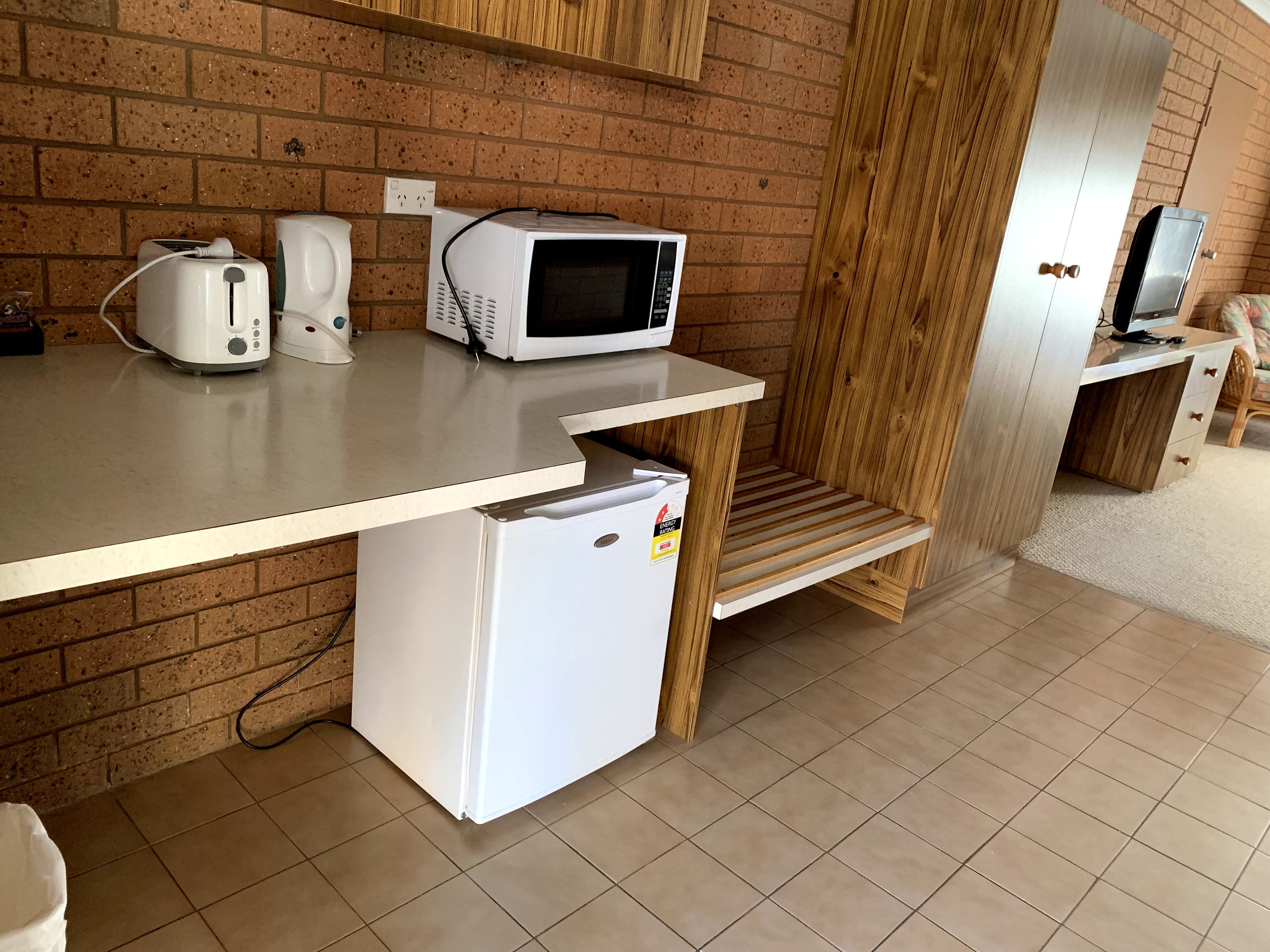Uma cozinha compacta com micro-ondas, torradeira e geladeira em uma bancada.