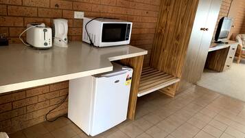 Uma cozinha compacta com micro-ondas, torradeira e geladeira em uma bancada.
