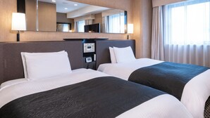 Quarto de hotel com duas camas, painel de controle, um espelho grande e uma janela com cortinas.
