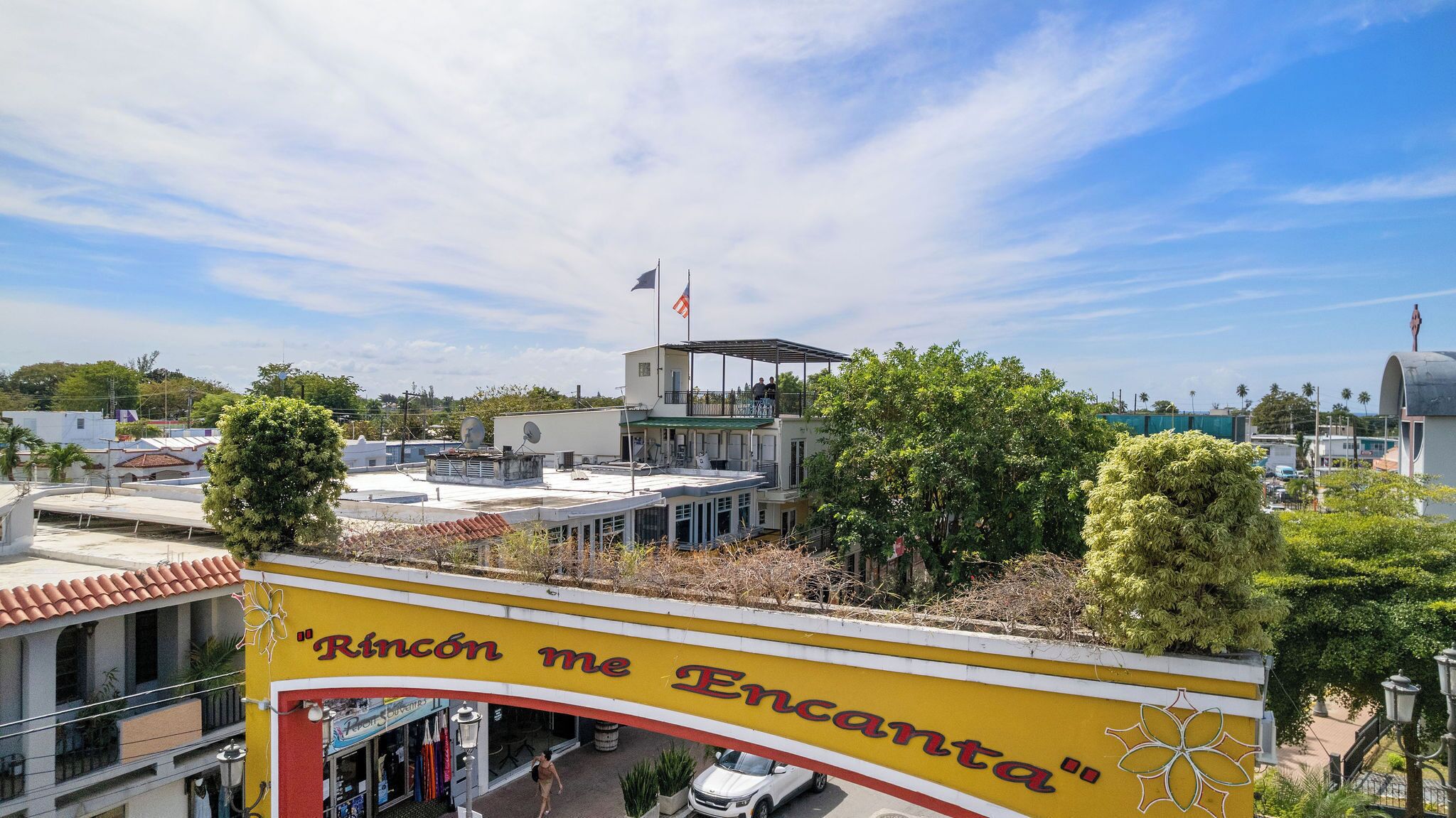 Um edifício com uma bandeira, uma área coberta e uma placa que diz 'Rincón me Encanta'.