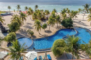 Uma área de piscina com design curvo, cercada por palmeiras e cadeiras de praia.