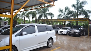 Uma área de estacionamento coberta com vários veículos, incluindo um SUV branco e uma caminhonete preta.