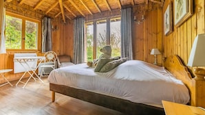 Quarto de cabana de madeira com uma cama grande, uma escrivaninha e uma cadeira.