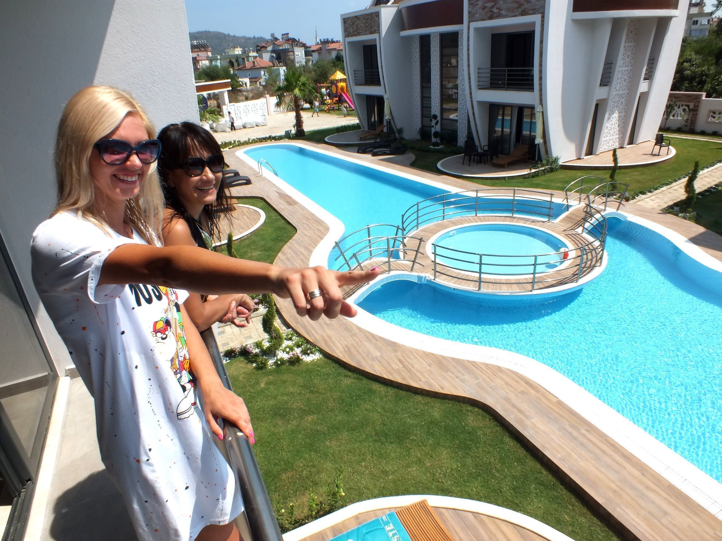 Piscina com deck de madeira e um recurso aquático circular.