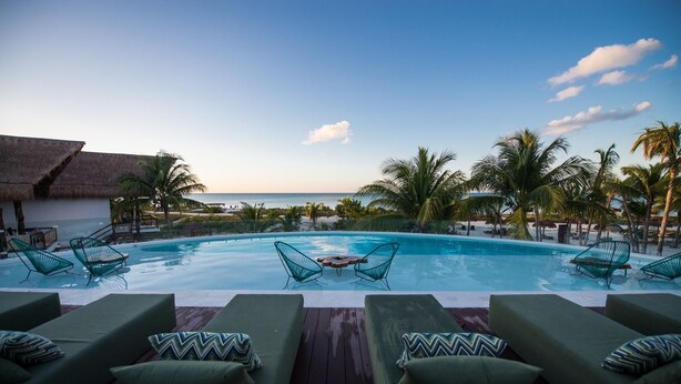 Área da piscina com espreguiçadeiras e vista para o oceano.