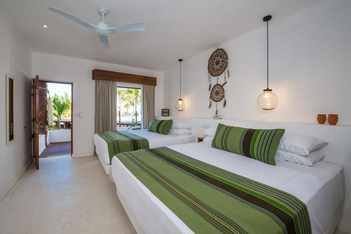 Quarto de hotel com duas camas, um ventilador de teto, um sonho e vista para o exterior.