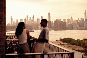 Silhueta urbana com edifícios notáveis, incluindo o Empire State Building, vista de uma varanda com guarda-corpo.