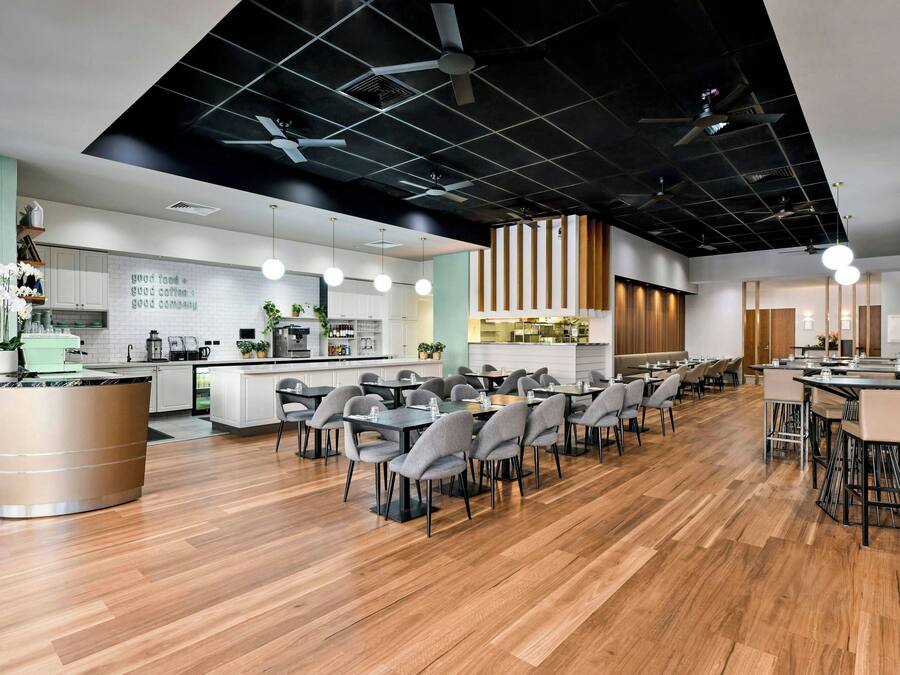 Um restaurante moderno com uma ilha central, várias mesas de jantar e uma área de cozinha ao fundo.