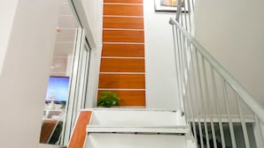Escadaria com guarda-corpo branco e degraus de madeira que levam a um nível inferior.