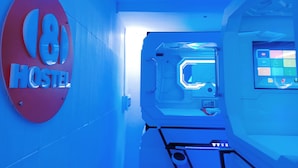 Interior de um hostel futurista, com uma placa de destaque 'Hostel', um painel de controle e uma interface digital.