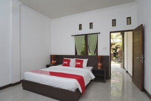Um quarto com cama, mesas de cabeceira, uma janela com cortinas e uma porta que dá para um pátio.