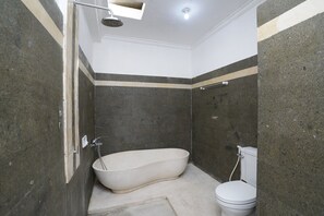 Uma casa de banho com uma banheira independente, sanita e chuveiro.