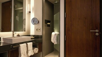 Uma casa de banho moderna com um espelho grande, uma pia e um porta-toalhas.