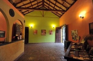 Uma área de recepção com piso de azulejos, balcão de recepção e parede com quadros emoldurados.
