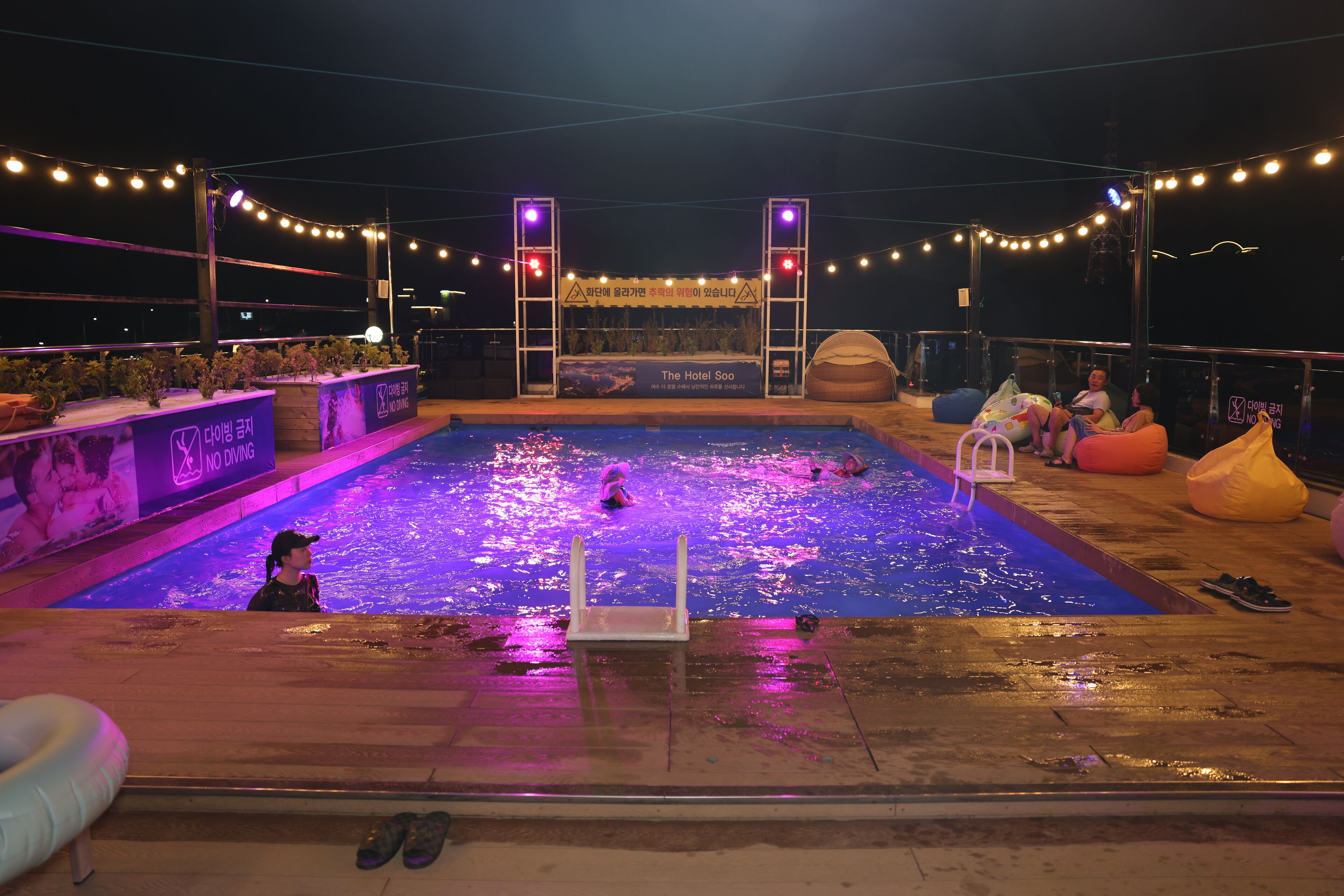 Área de piscina no terraço, com placa indicando 'The Hotel Soo' e aviso de 'Não Mergulhar'.