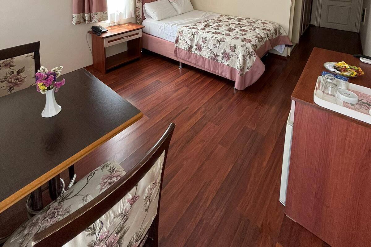 Quarto pequeno e bem arrumado, com uma cama de solteiro, mesa de cabeceira, escrivaninha e uma cadeira.