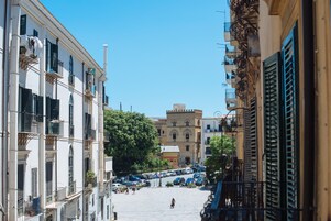 Rua com edifícios em ambos os lados, céu claro e uma torre ao longe.