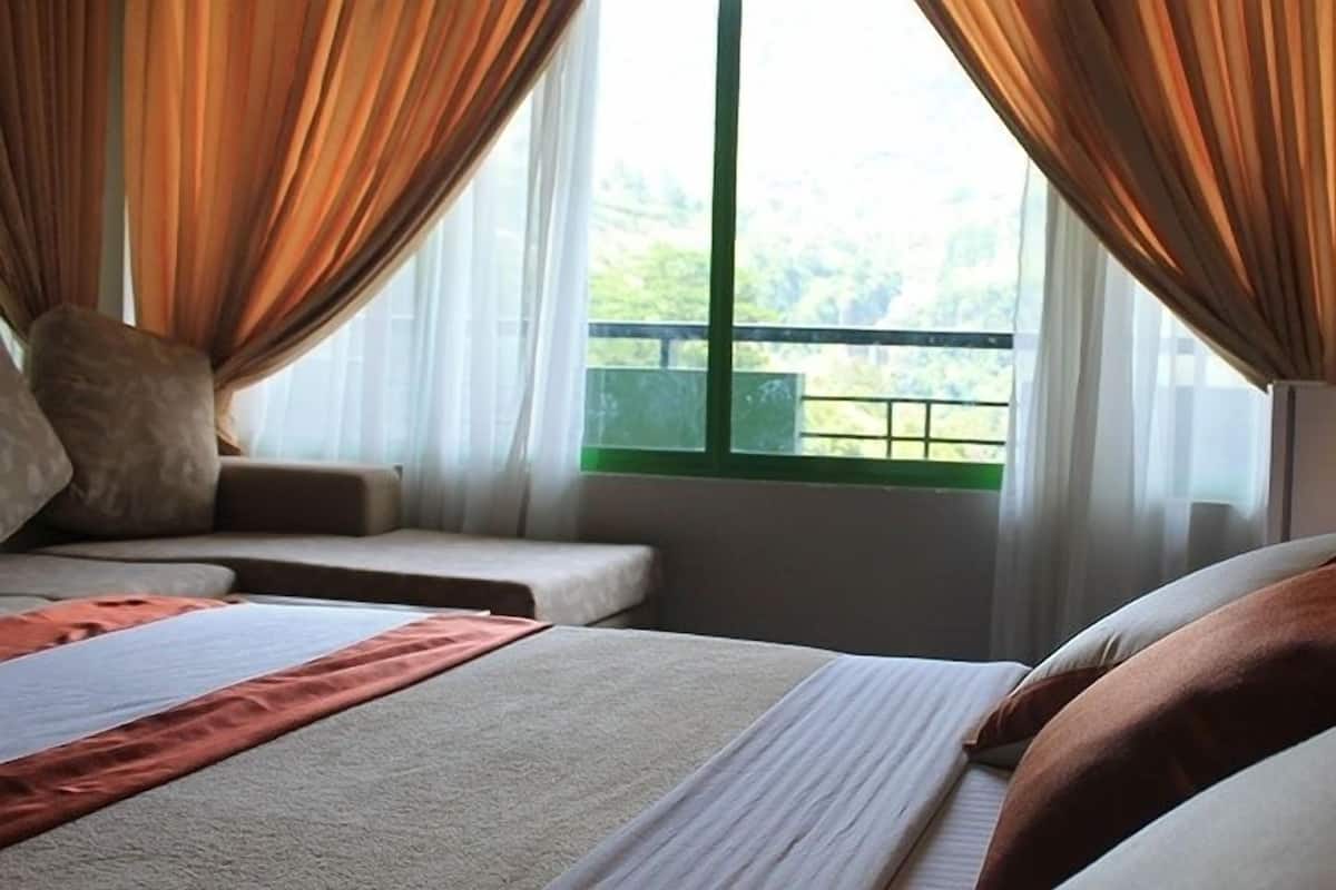 Quarto de hotel com cama, sofá e janela com cortinas.
