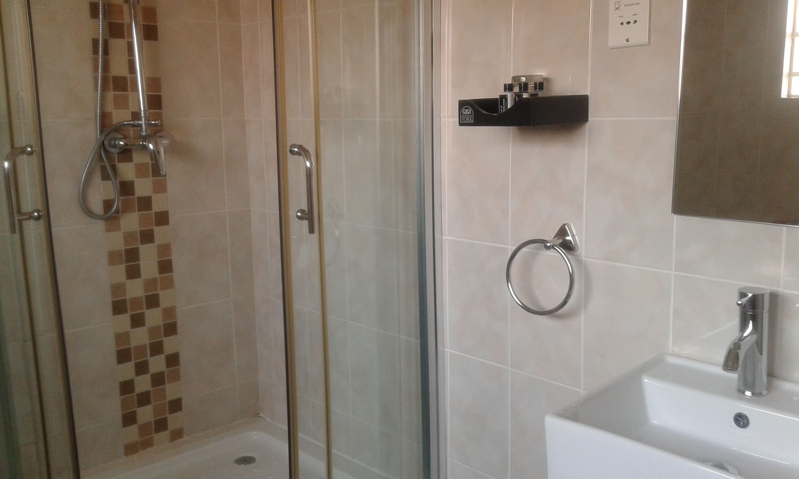 Casa de banho com cabine de duche em vidro, uma sanita branca e um suporte para toalha.