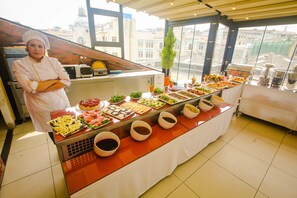 Buffet montado com diversos alimentos e um chef ao lado.