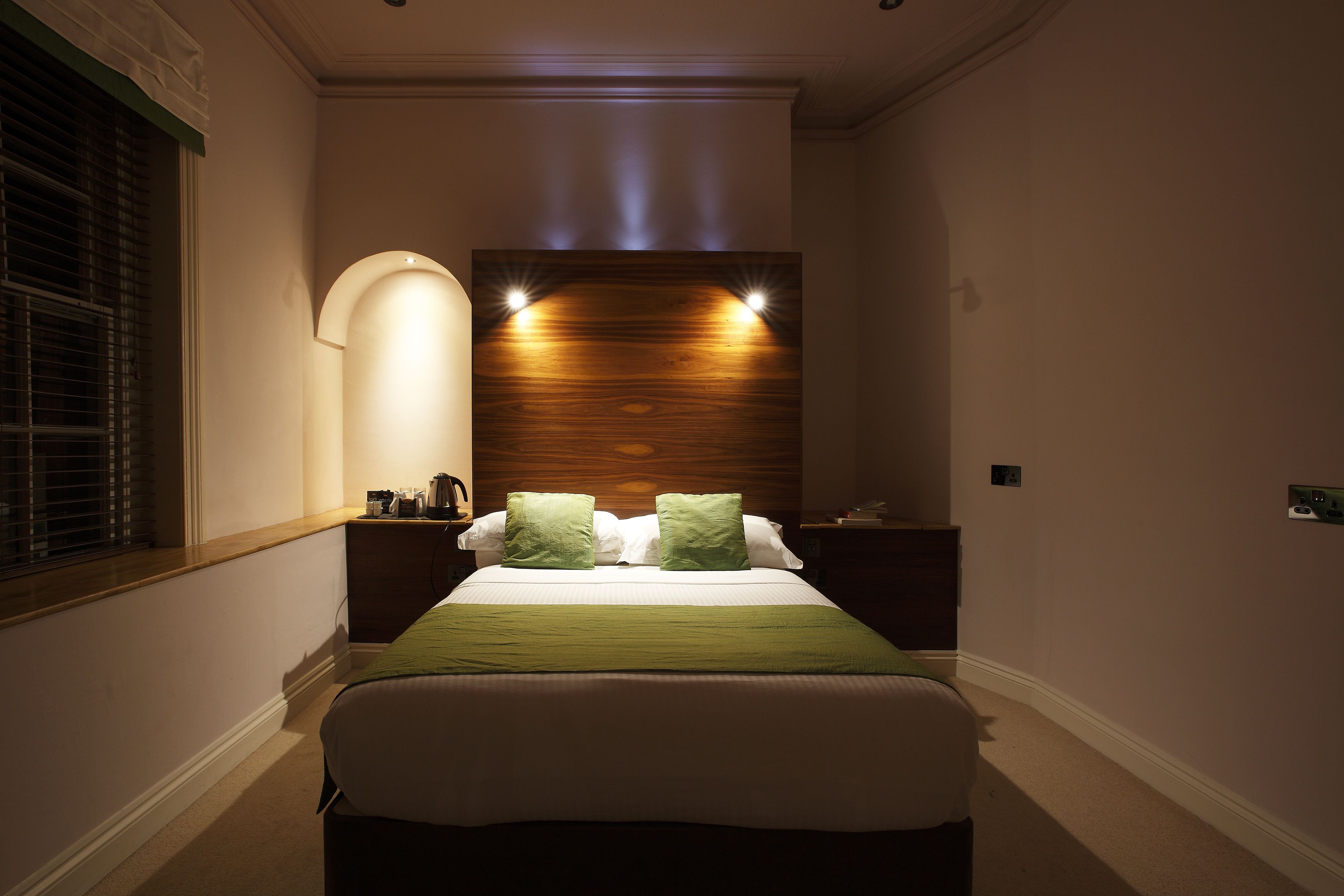 Quarto bem arrumado com uma cama grande, cabeceira de madeira e mesa de cabeceira com abajur.