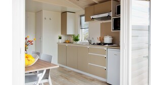 Cozinha compacta com área de refeições, piso de madeira e vista para o exterior.